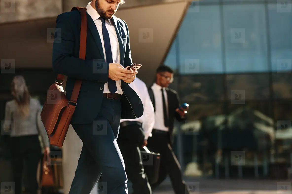 Business People Using Mobile Phone While Walking On Street To Of Photo ...