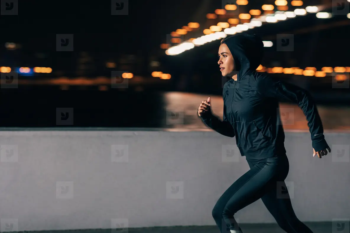 Side View Of A Woman In Hoodie Running At Night. Middle East Female ...