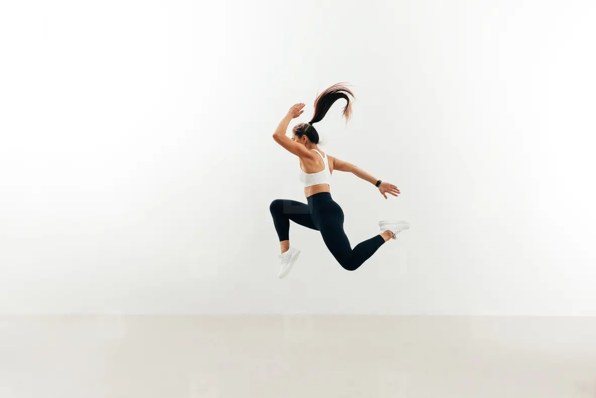 Side View Of Woman With Muscular Body Jumping Against White Wall Photo ...