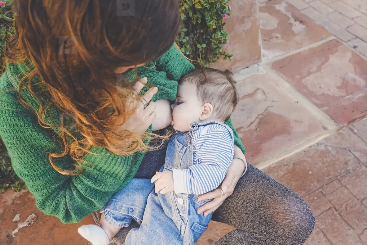 Young Woman Breastfeeding Her Baby Outdoors In A Sunny Day Photo ...