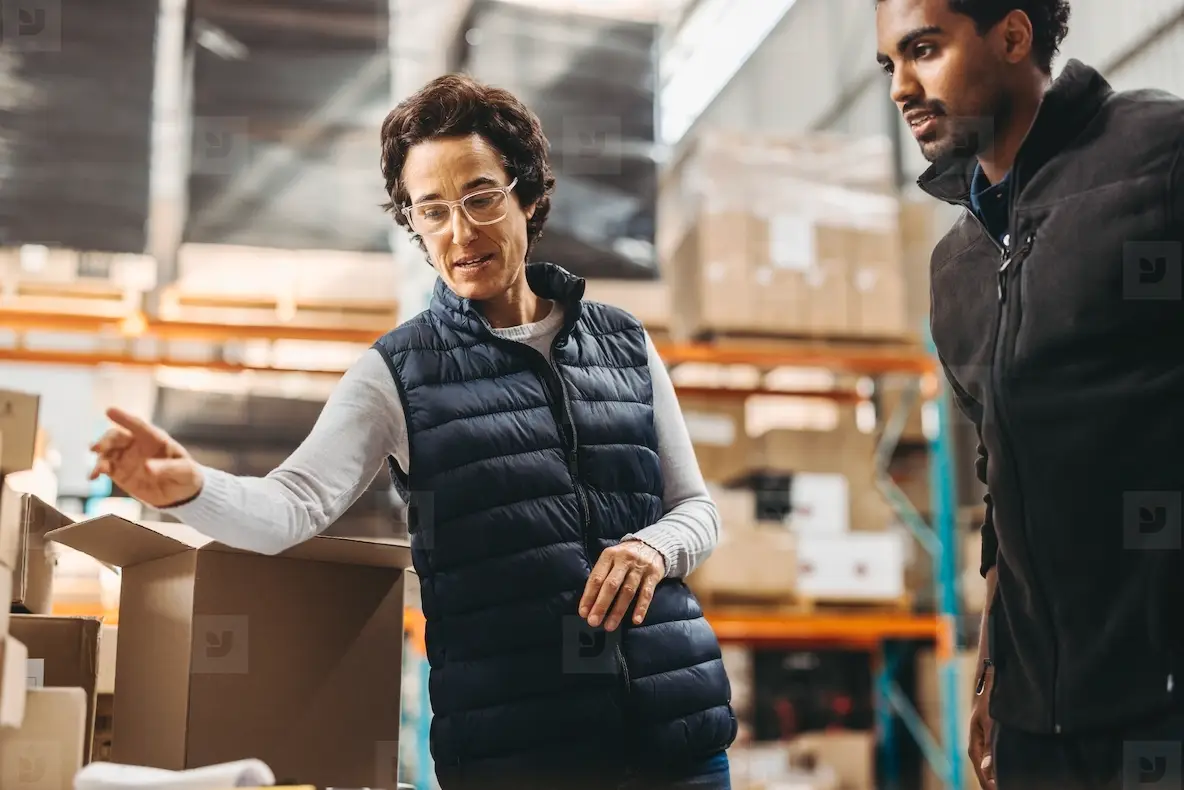 Female Logistics Manager Training An Employee In A Warehouse Photo ...