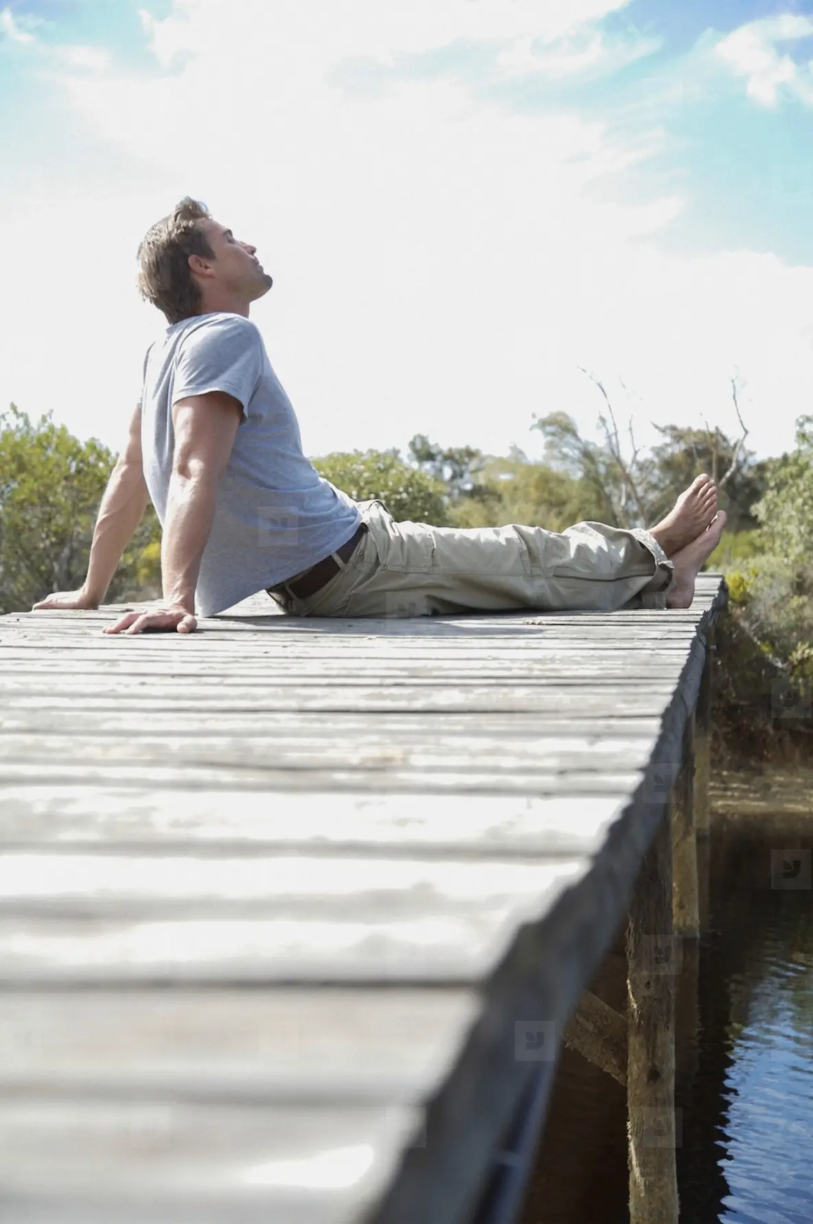 Portrait Of Barefoot Man Sitting On A Boardwalk By A River Photo ...