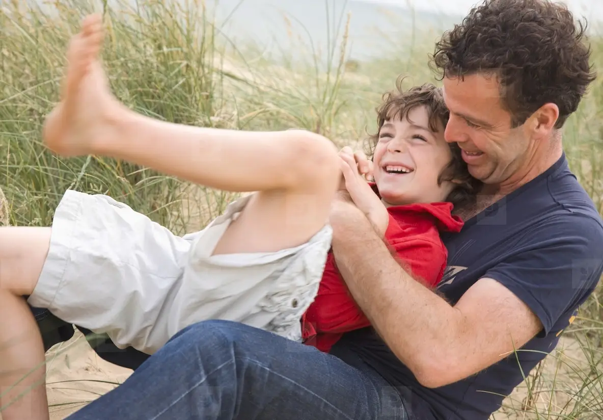 Father And Son Sitting On A Beach Smiling And Fighting Photo (279397 ...