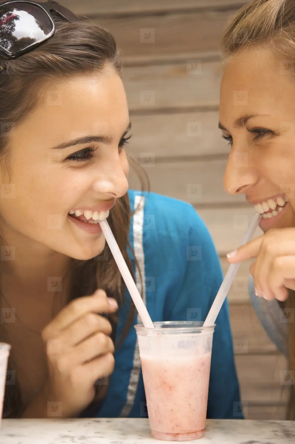 Two Smiling Teenaged Girls Drinking Milk-shake With A Straw From The ...