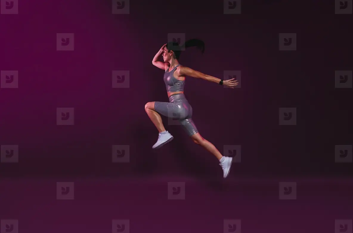 Side View Of A Young Slim Woman Jumping Against A Magenta Backdrop ...