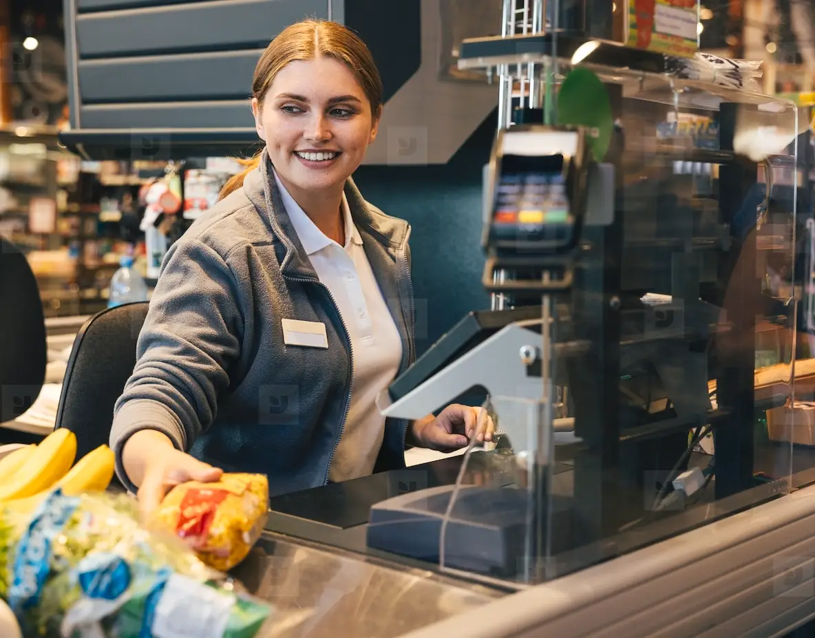 Smiling Female Cashier Working At The Cash Register And Moving Scanned ...