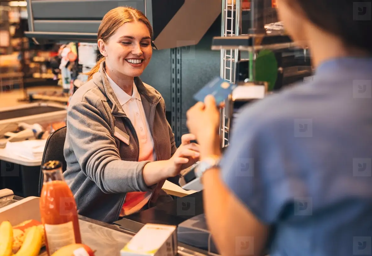Smiling Cashier In A Grocery Store Receiving Payment From A Customer ...